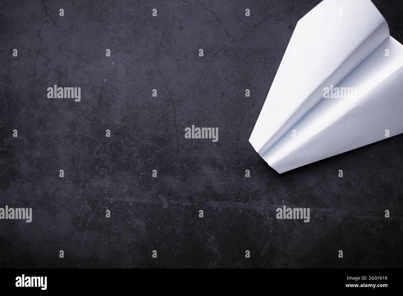 Paper airplane on the table. Origami model on a dark background ...