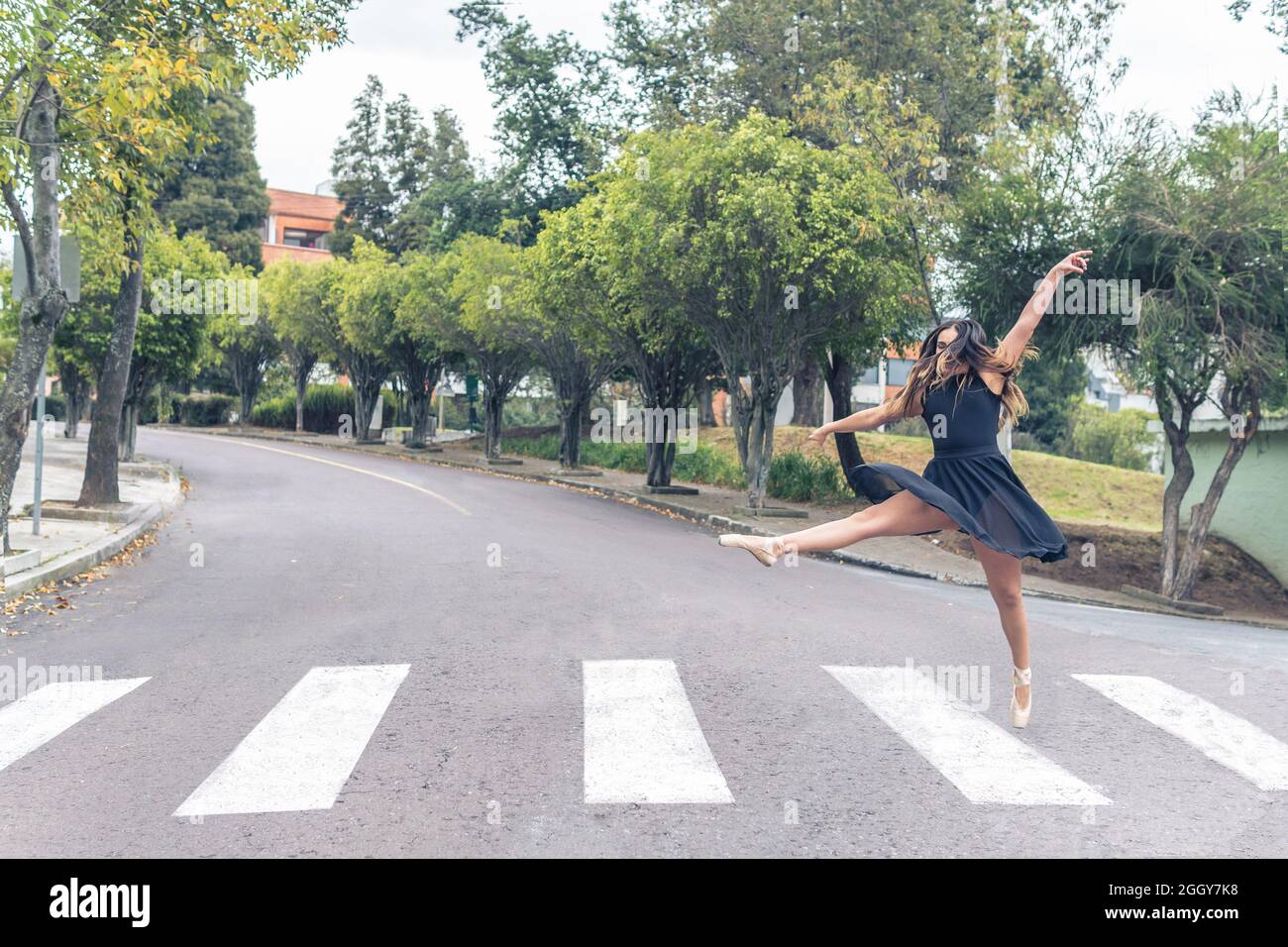 Teenager girl dancing with ballet shoes on a pedestrian crossing in the ...
