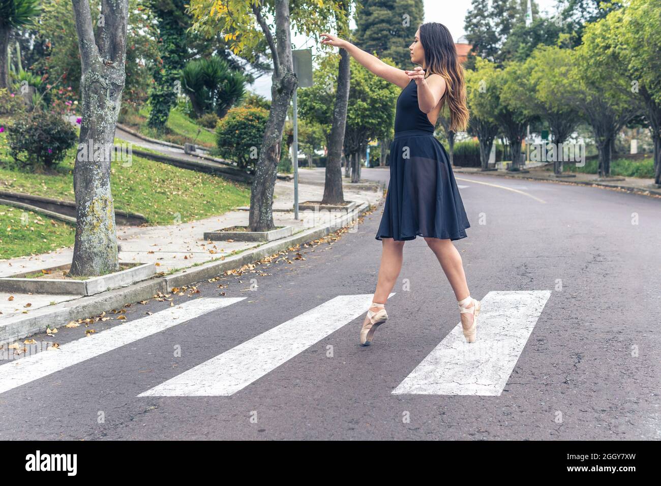 Latin female ballet dancer dancing on tiptoe on a pedestrian crossing ...