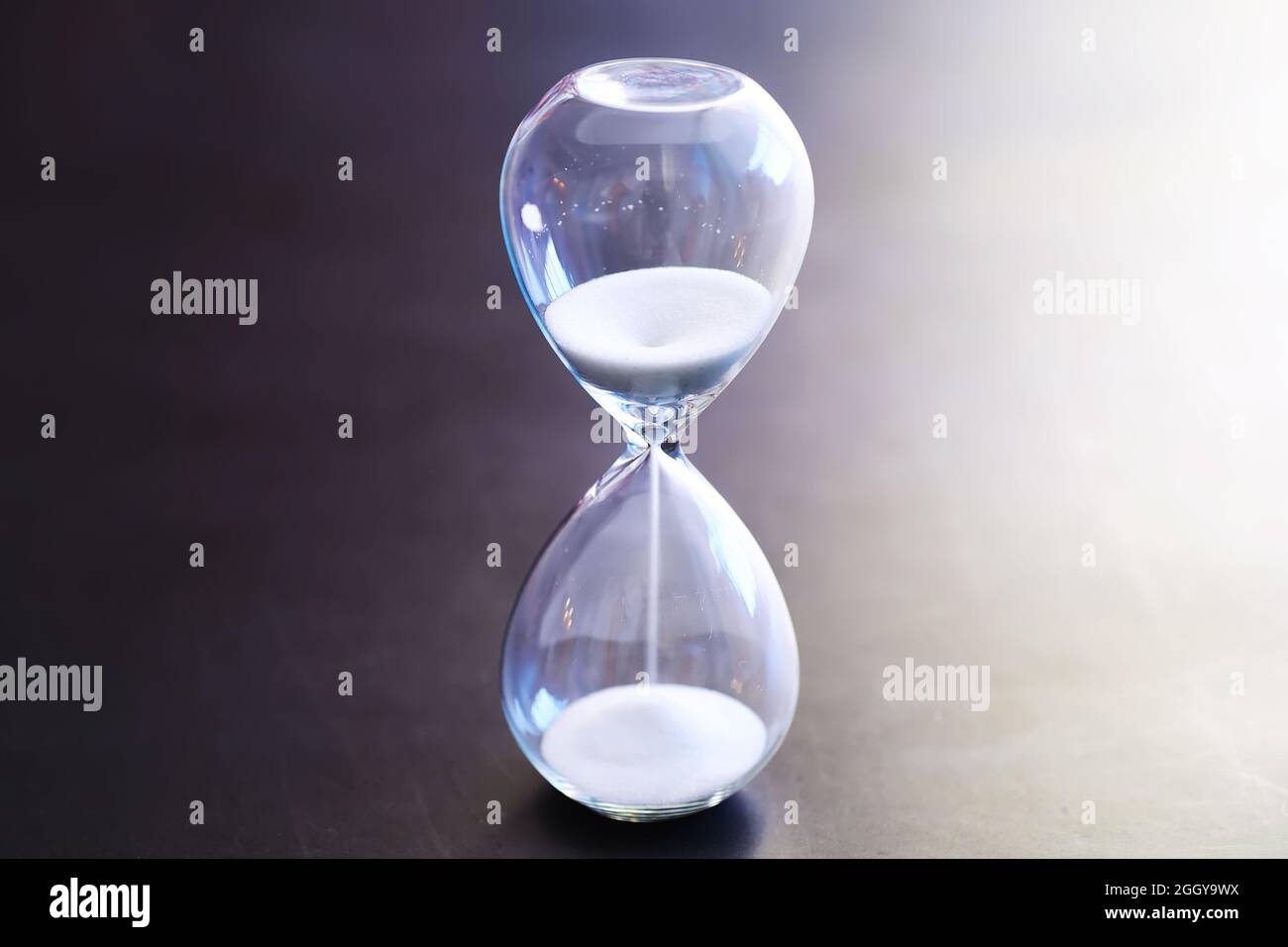 Sand running through the bulbs of an hourglass measuring the passing ...