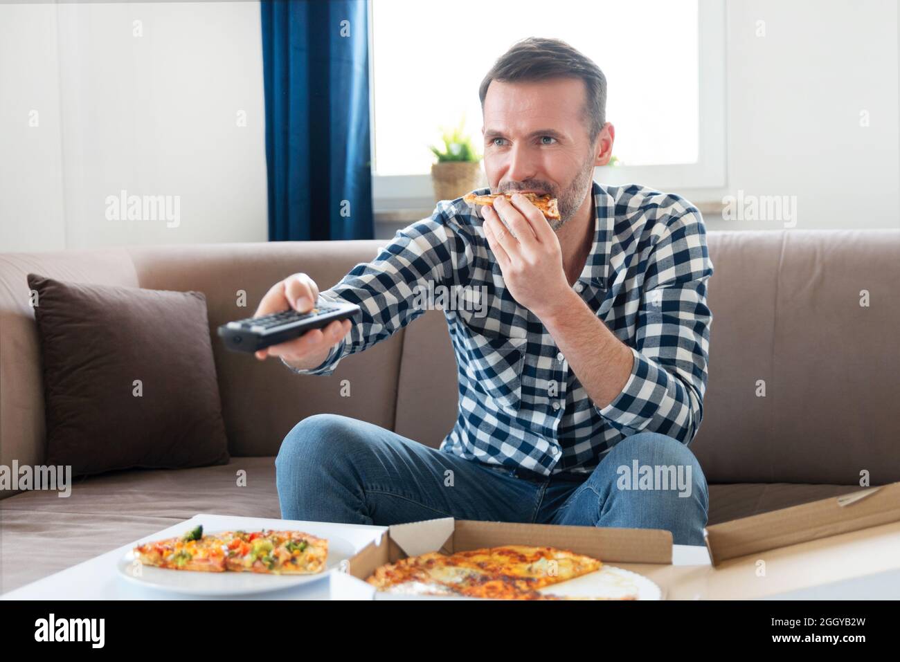 Man watching TV while eating pizza. Spending free time at home Stock ...
