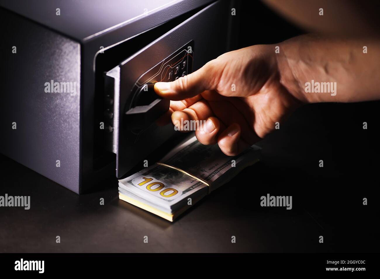 Steel safe with money. Hand putting password in the safety money box in ...
