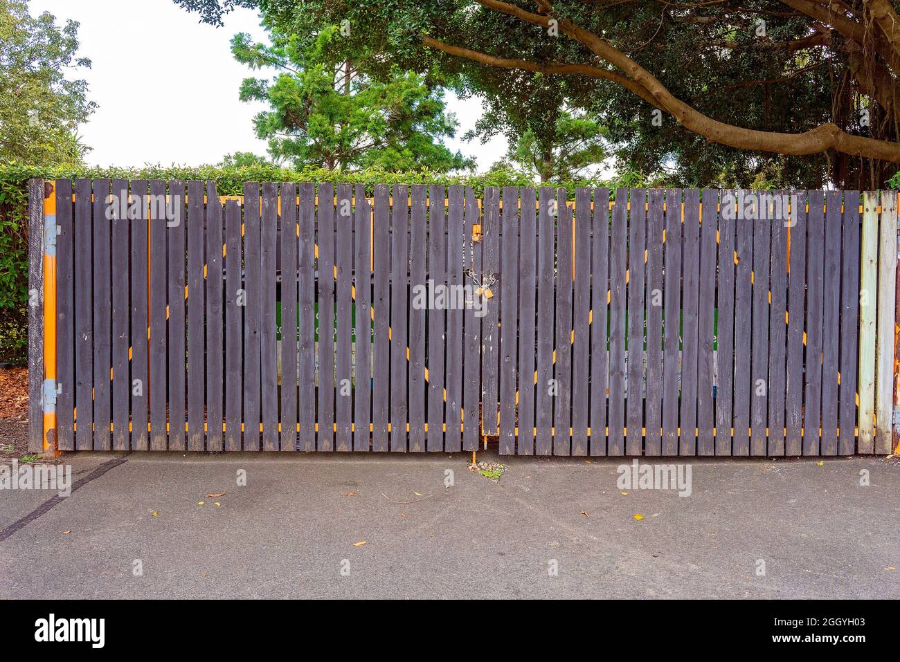 Locked gate hiding rubbish bins in front of a garden hedge at botanic ...