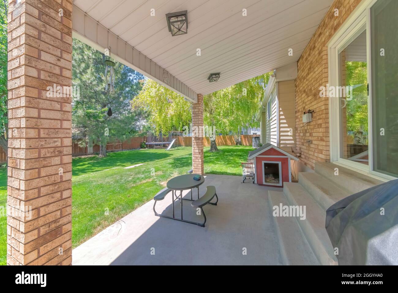 Fenced backyard of a house with sliding glass back door and large green ...