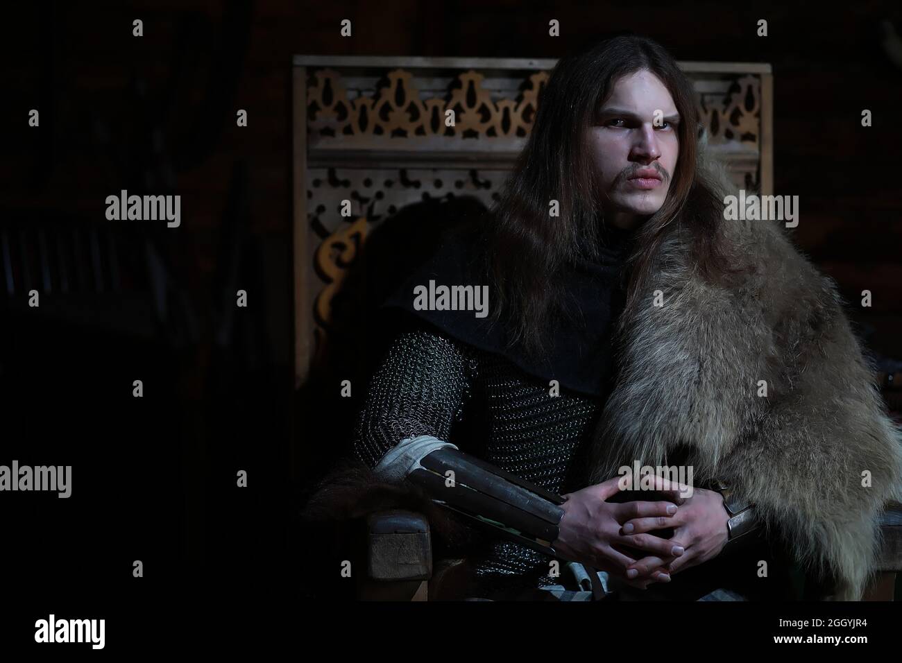 A mighty hero with long hair in chain mail armor in an ancient hall ...