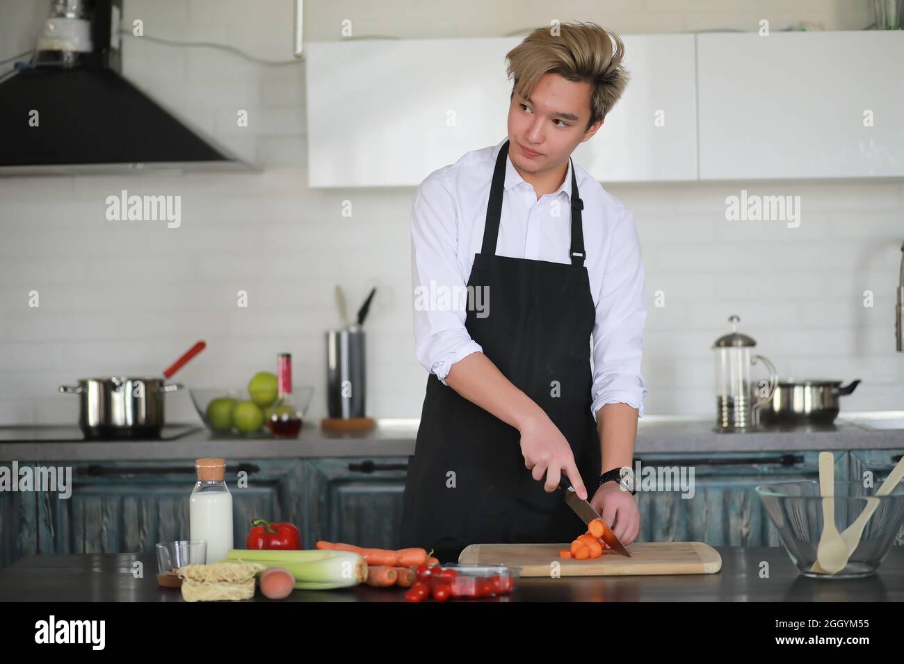 A young Asian cook in the kitchen prepares food in a cook suit Stock ...