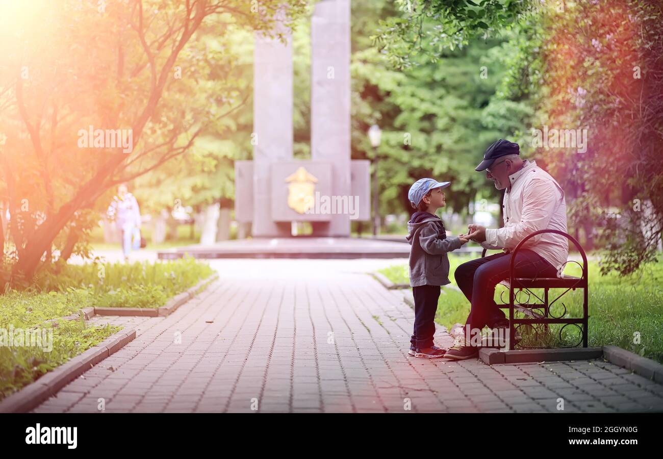 Grandpa is walking with her grandson in a spring park. Grandson and ...