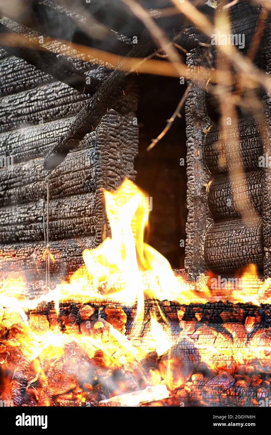 Wooden house after the fire. Coals on the logs. The ashes of the house ...