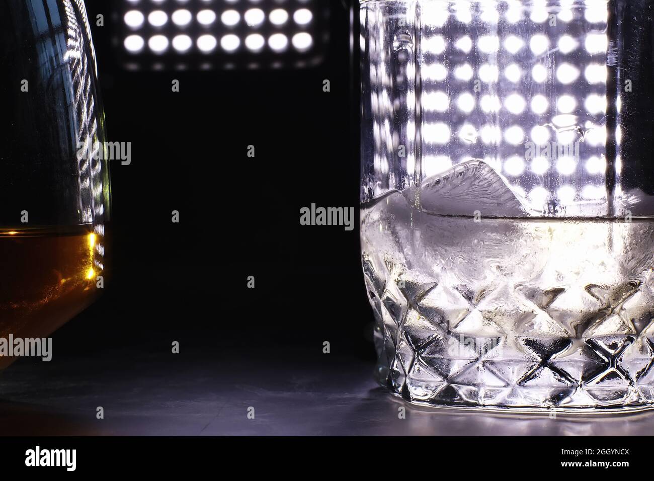 A glass of hard alcohol with ice on a bar counter. Whiskey with soda in ...