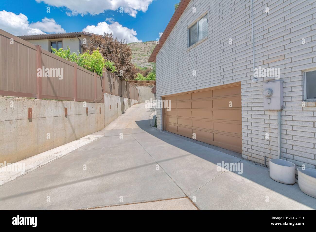 Uphill curved driveway beside the garage with sliding window and white ...