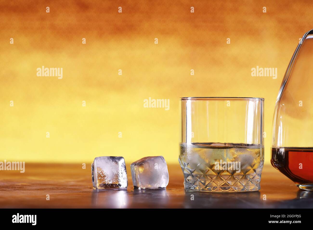 A glass of hard alcohol with ice on a bar counter. Whiskey with soda in ...