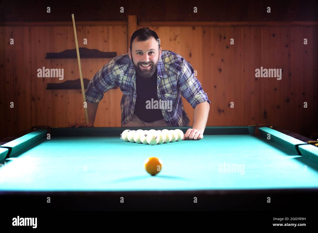 A man with a beard plays a big billiard. Party in 12-foot pool ...