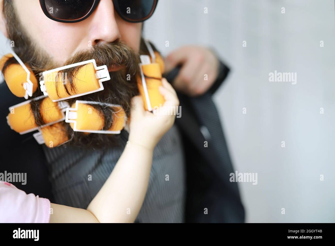 Baby infant hands grab beard of man.Cheerful hipster man curlers in a ...