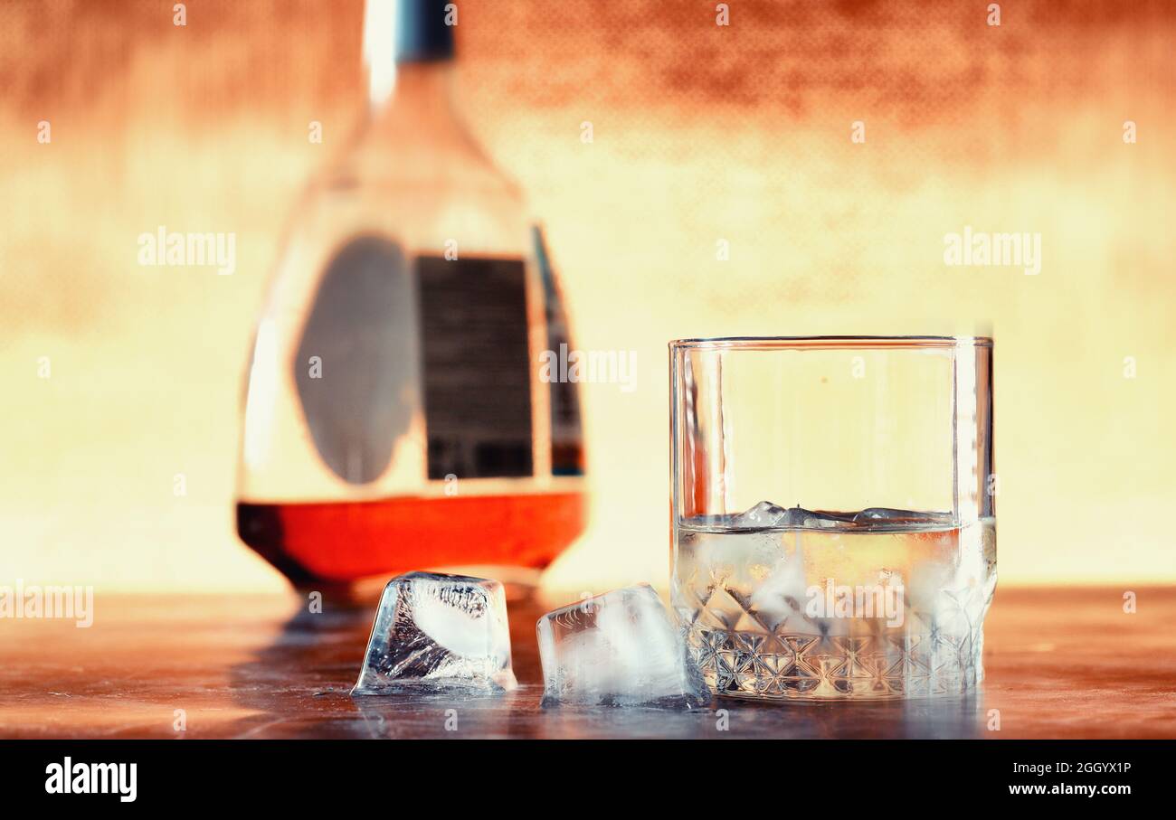 A glass of hard alcohol with ice on a bar counter. Whiskey with soda in ...