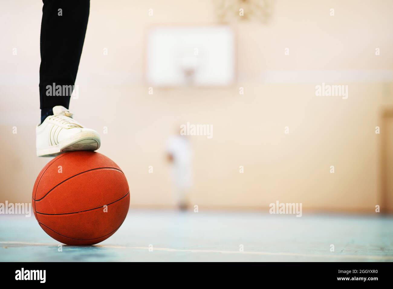 A human foot rest on the basketball on concrete floor. Photo of one ...