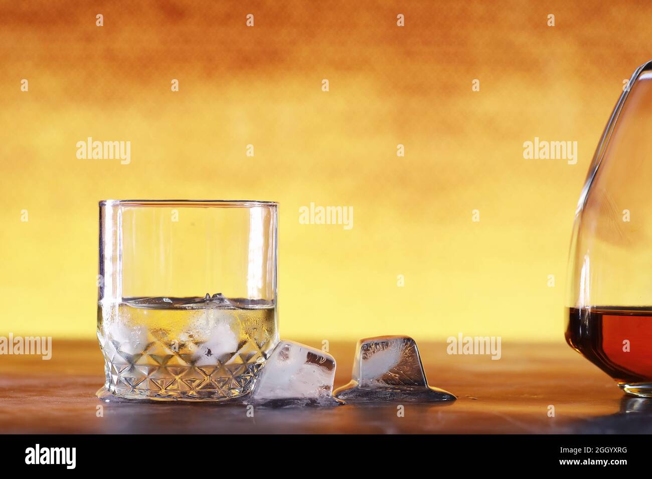 A glass of hard alcohol with ice on a bar counter. Whiskey with soda in ...