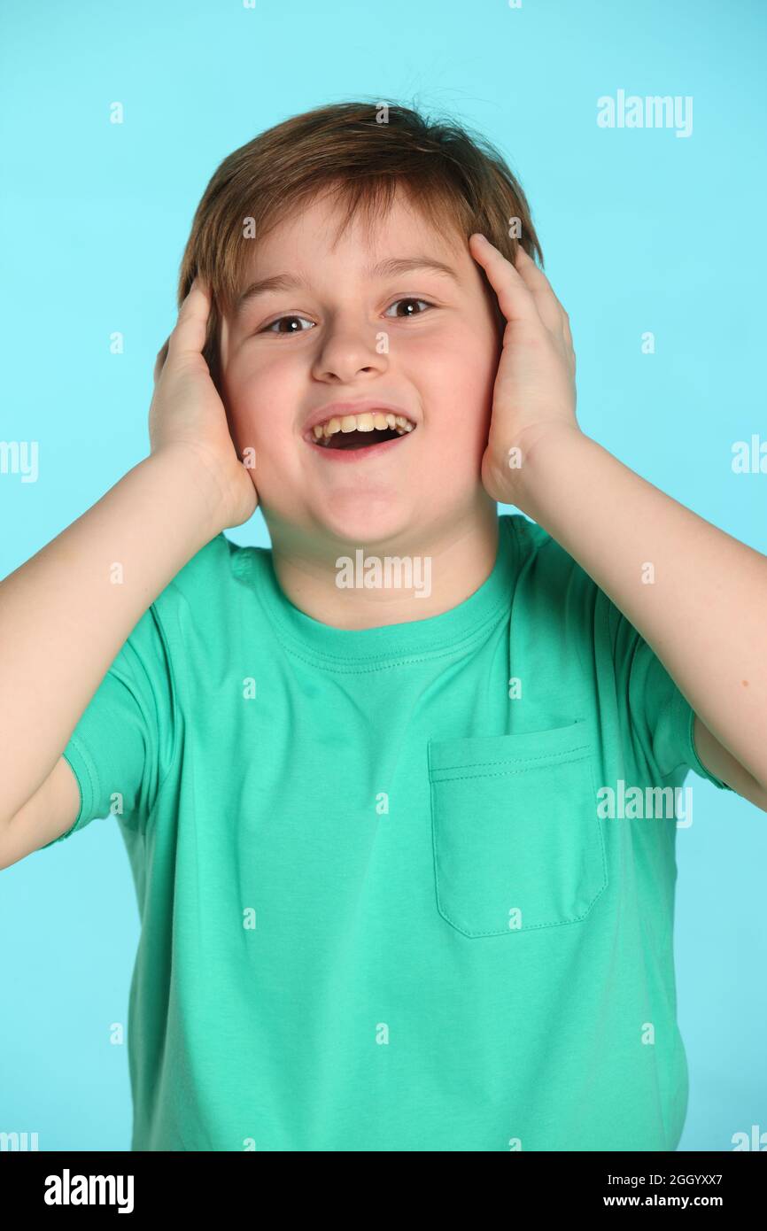 In this portrait, a handsome, cheerful young teenage boy hugs his head ...