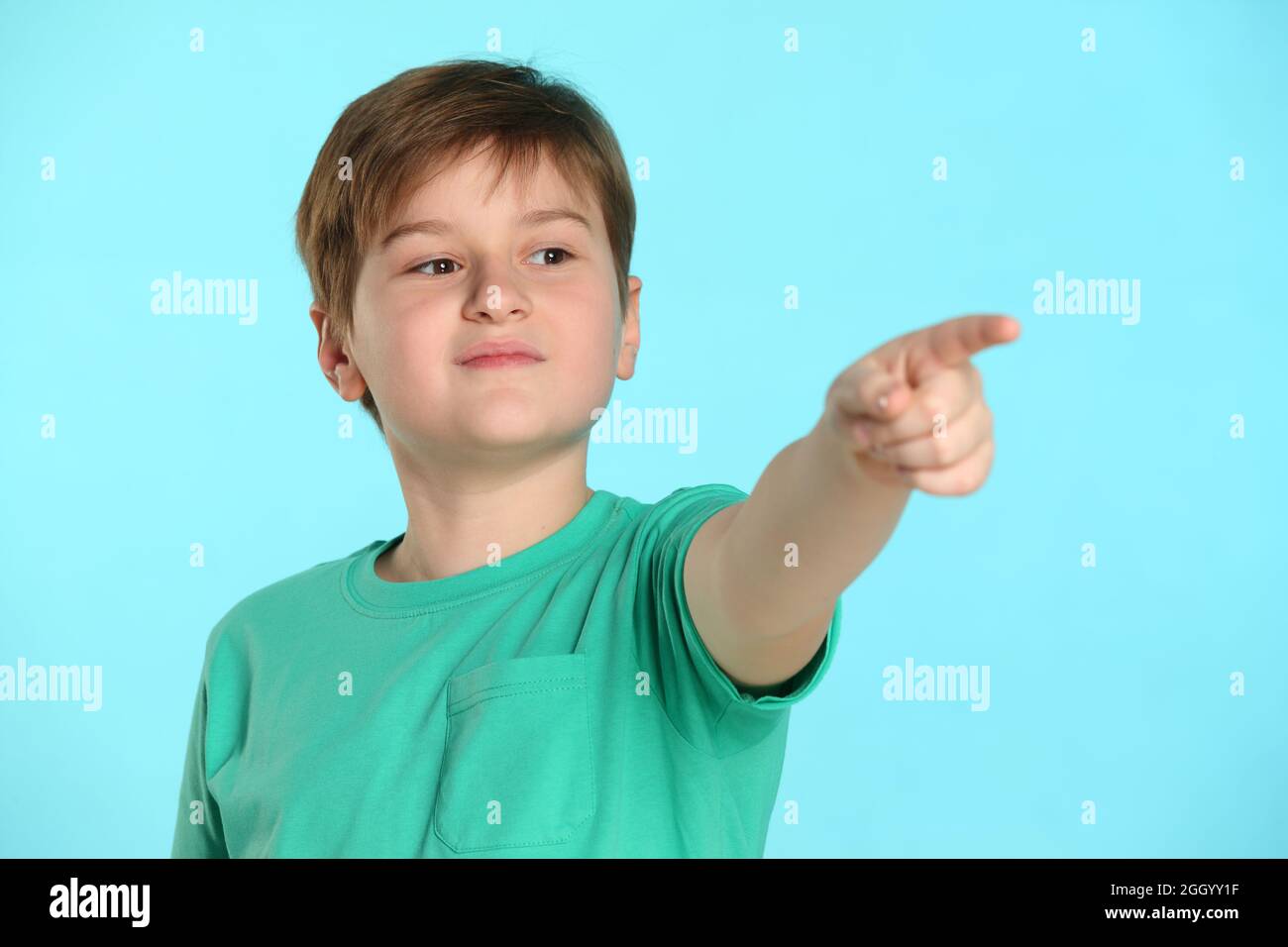 Portrait of a handsome cheerful teen boy points a finger and looks to ...