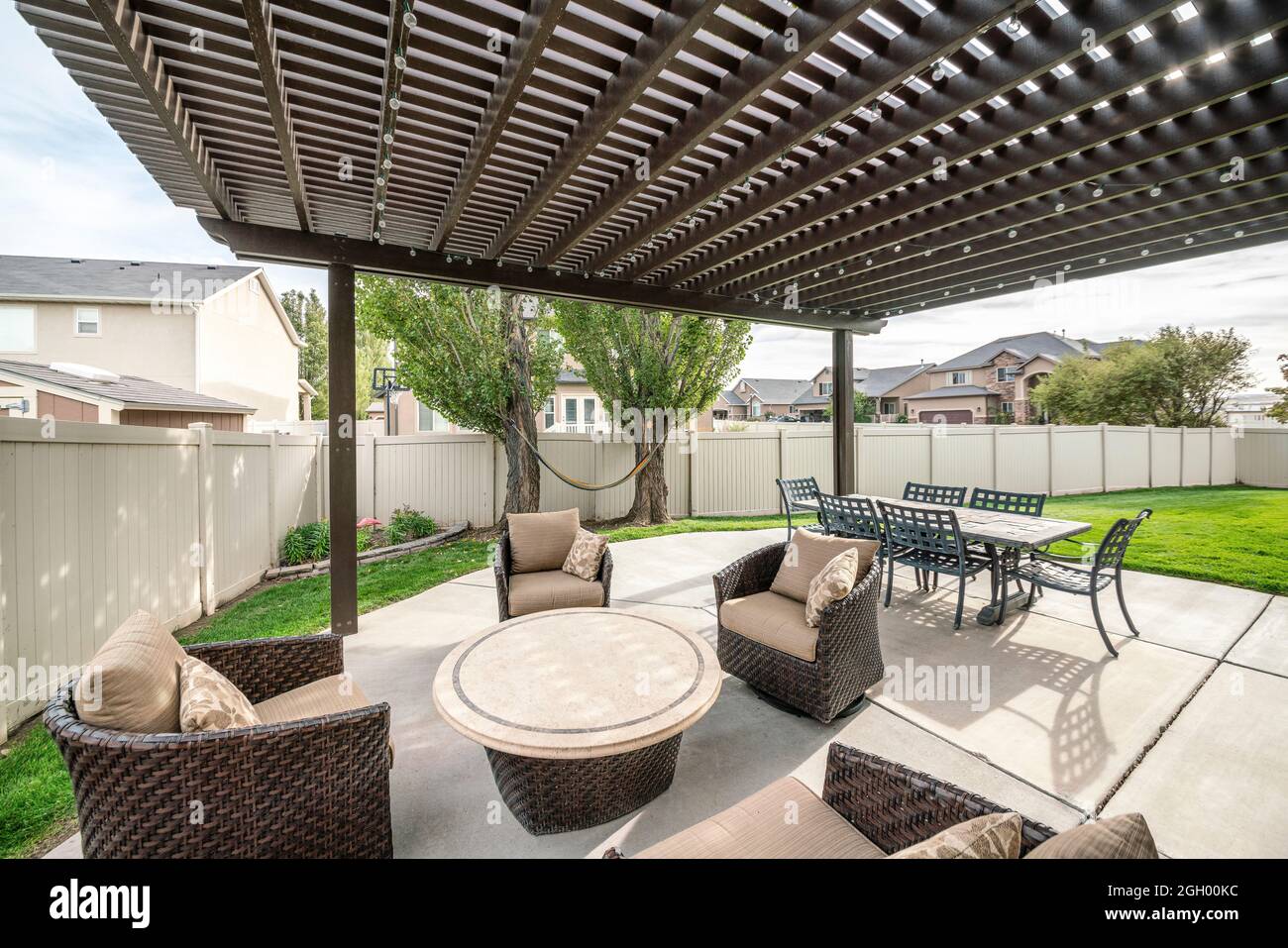 Woven armchairs with cushion and dining table under the pergola roof ...