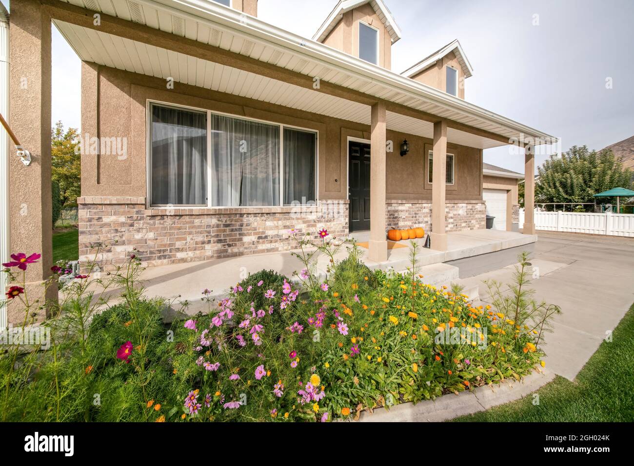 Side view of an exterior of a house with colorful planted flowers at ...