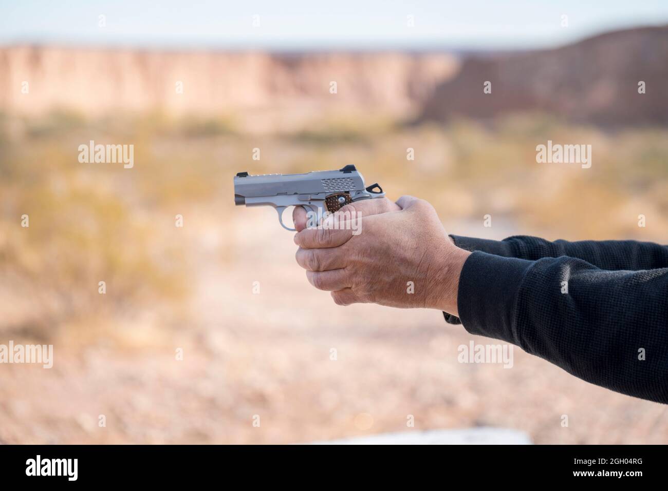 Hand of a man holding a small silver gun aiming on the left Stock Photo ...