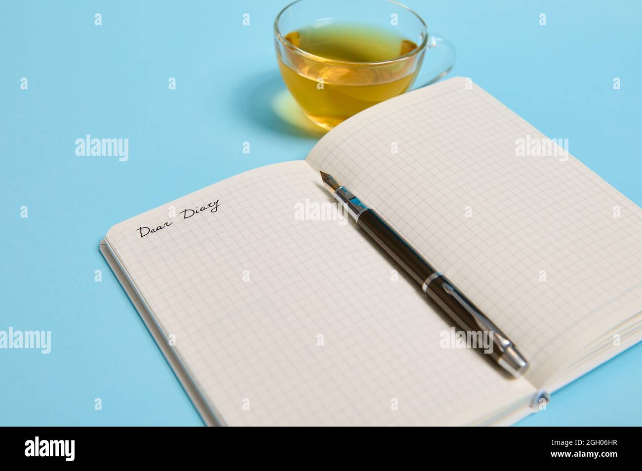 Open notepad with word Dear Diary and an ink pen next to a tea cup on ...