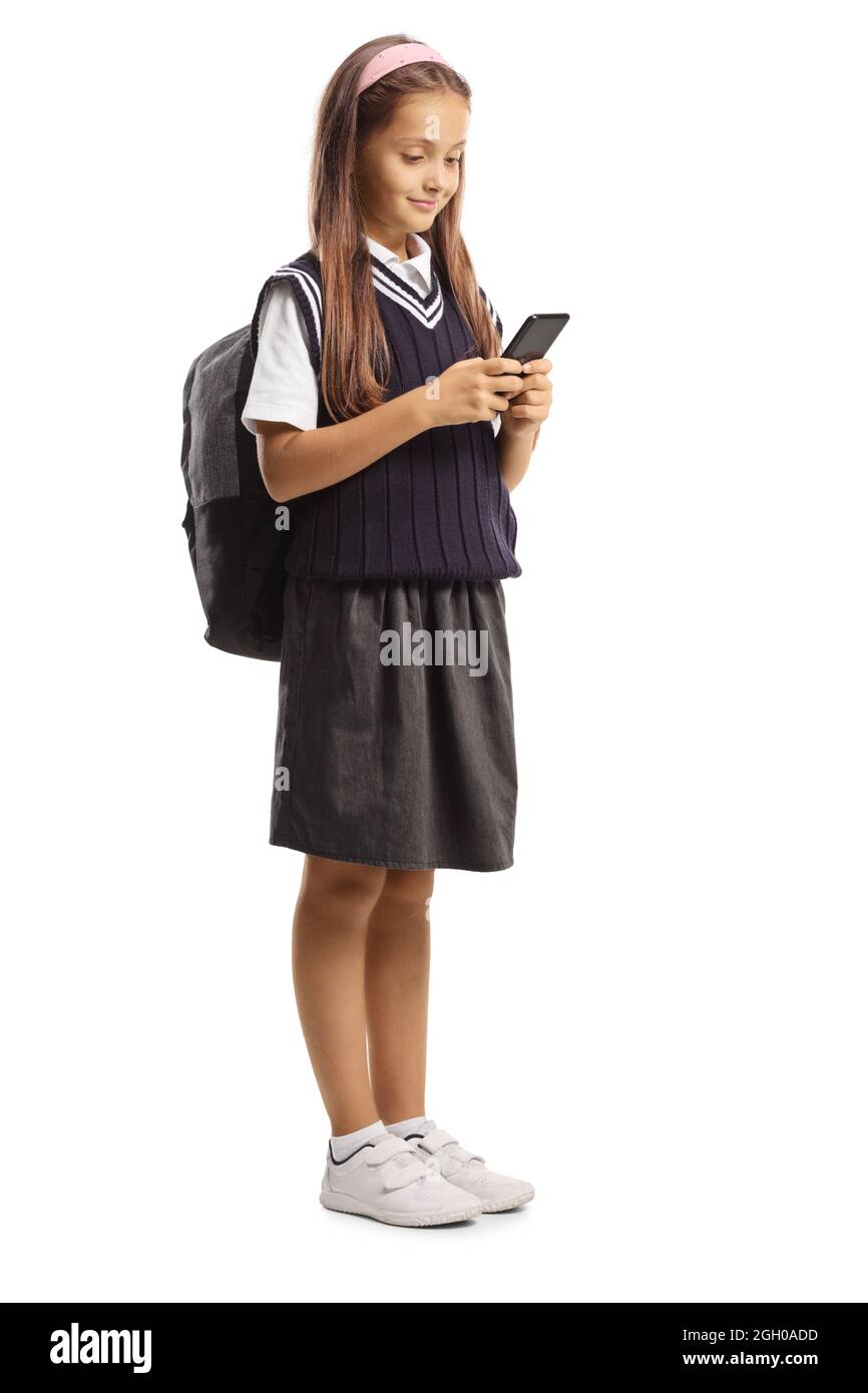 Schoolgirl in a school uniform standing and using a mobile phone ...