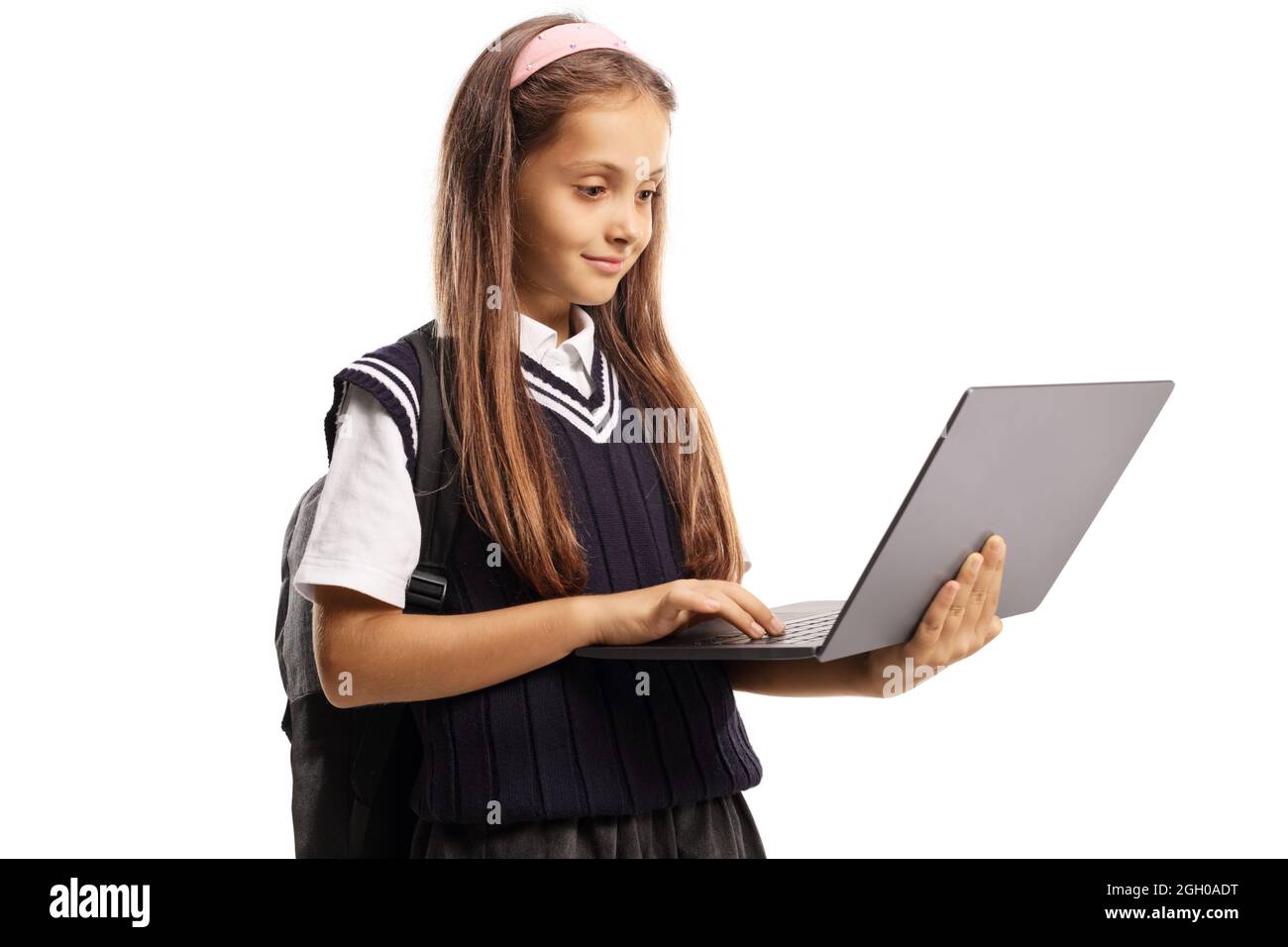 Schoolgirl standing and typing on a laptop computer isolated on white ...