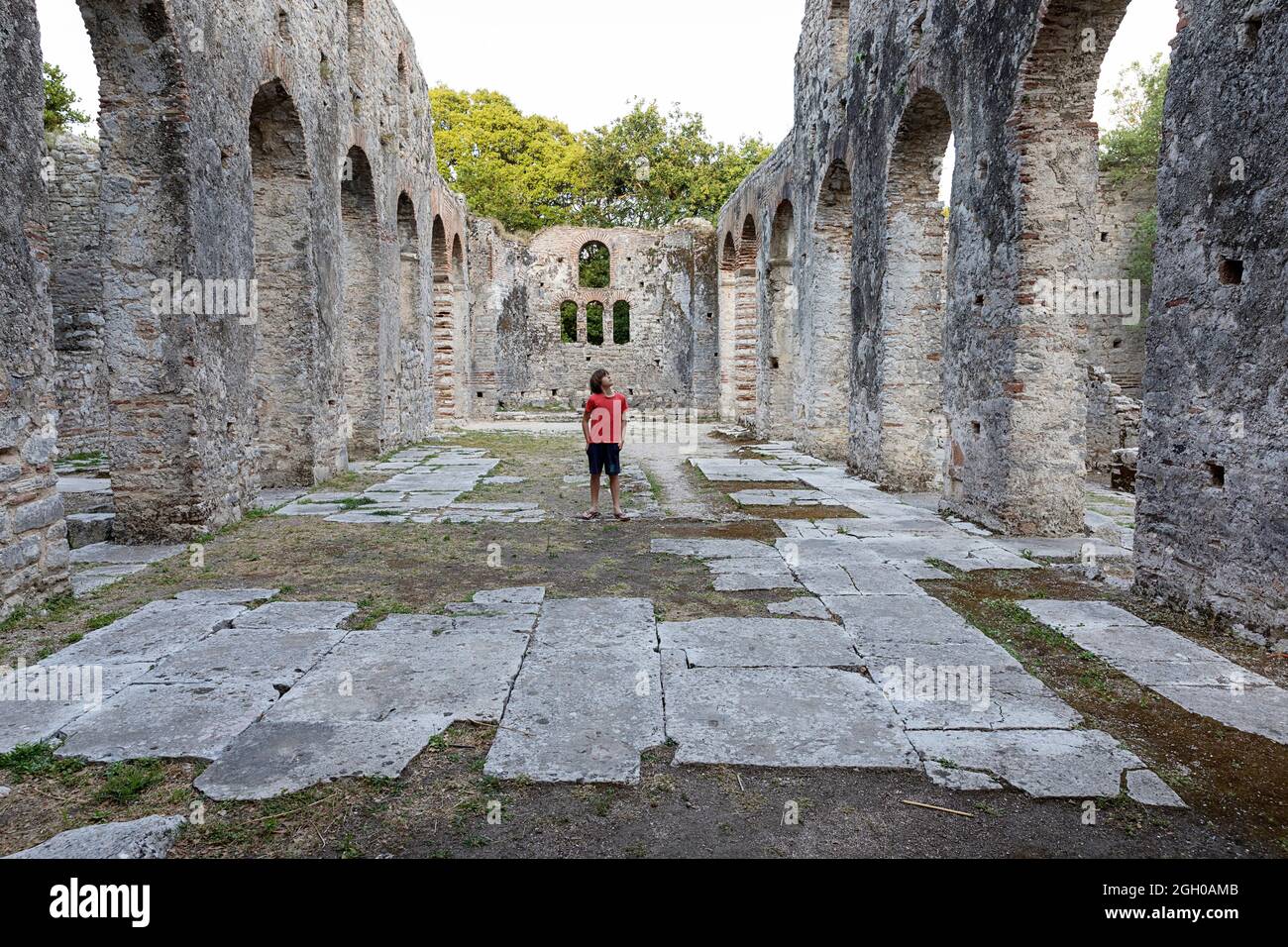 Boy standing in the middle of ruins of ancient city Butrint in Butrint ...