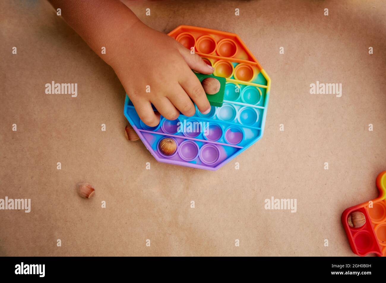 Kid invented a game with trendy pop it toy and hazel nuts. Game for ...