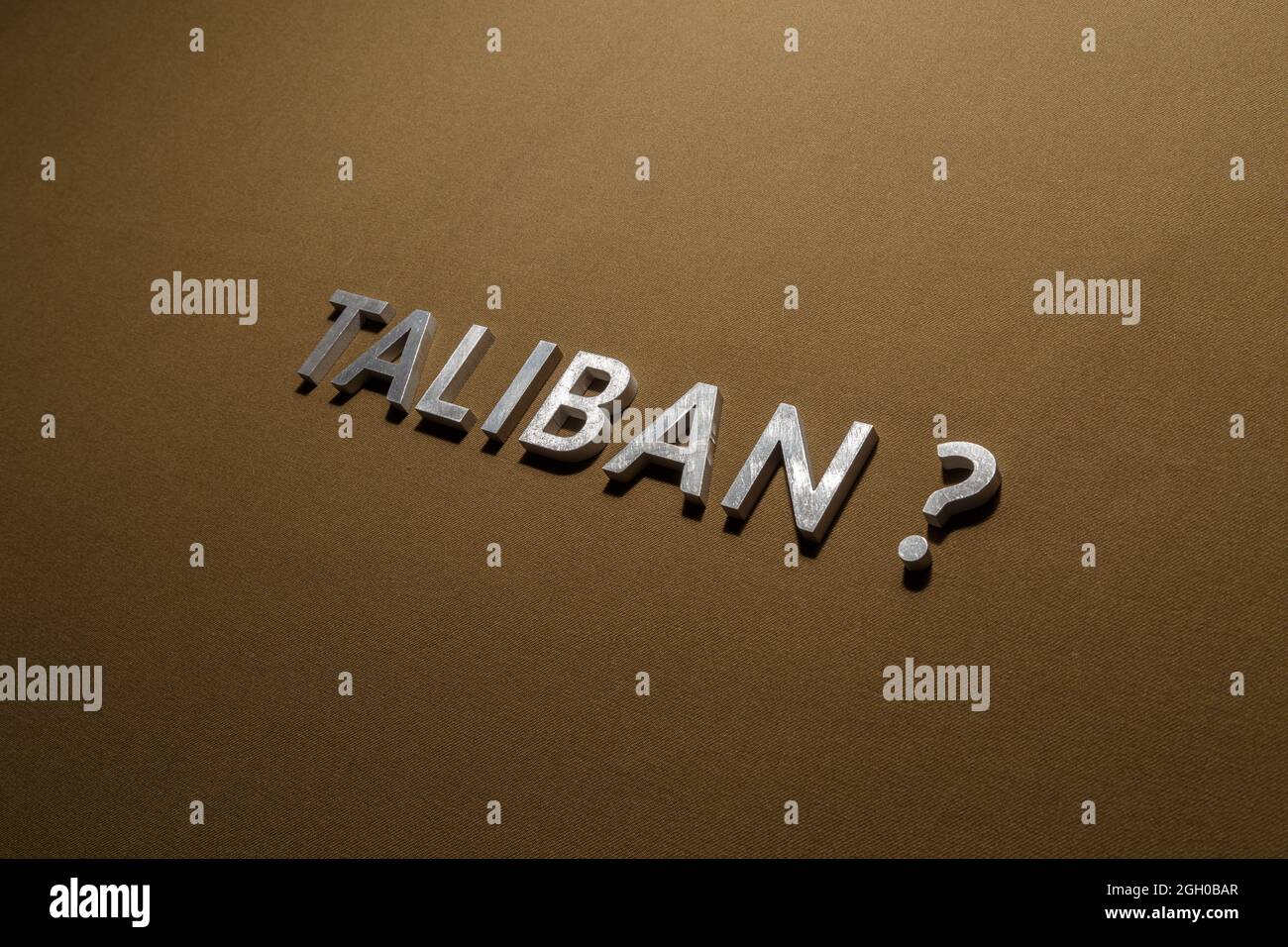 the question taliban laid with silver metal letters on rough tan khaki ...