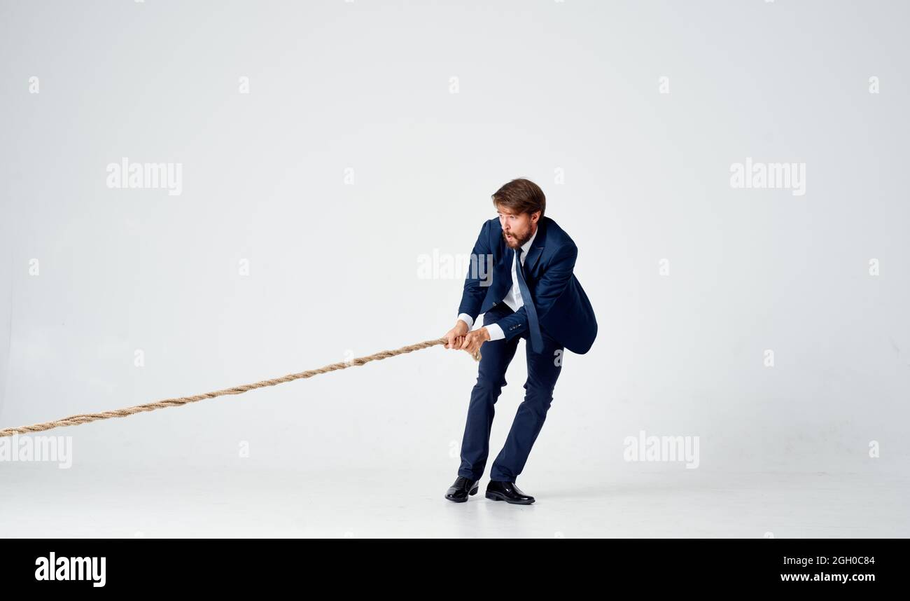 a man in a suit pulling a rope office manager teamwork Stock Photo - Alamy