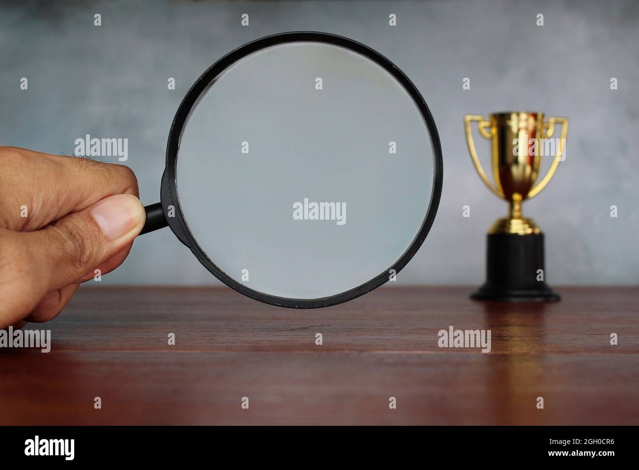 Magnifying glass and gold cup trophy on wooden table Stock Photo - Alamy