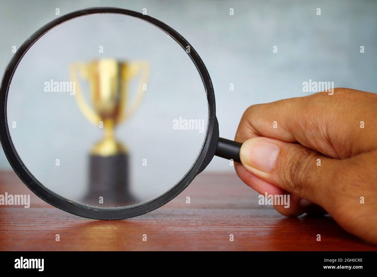 Magnifying glass and gold cup trophy on wooden table Stock Photo - Alamy