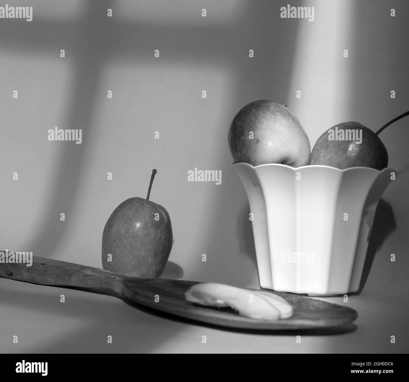 Grayscale of two apples in container next to a wooden spoon on the ...