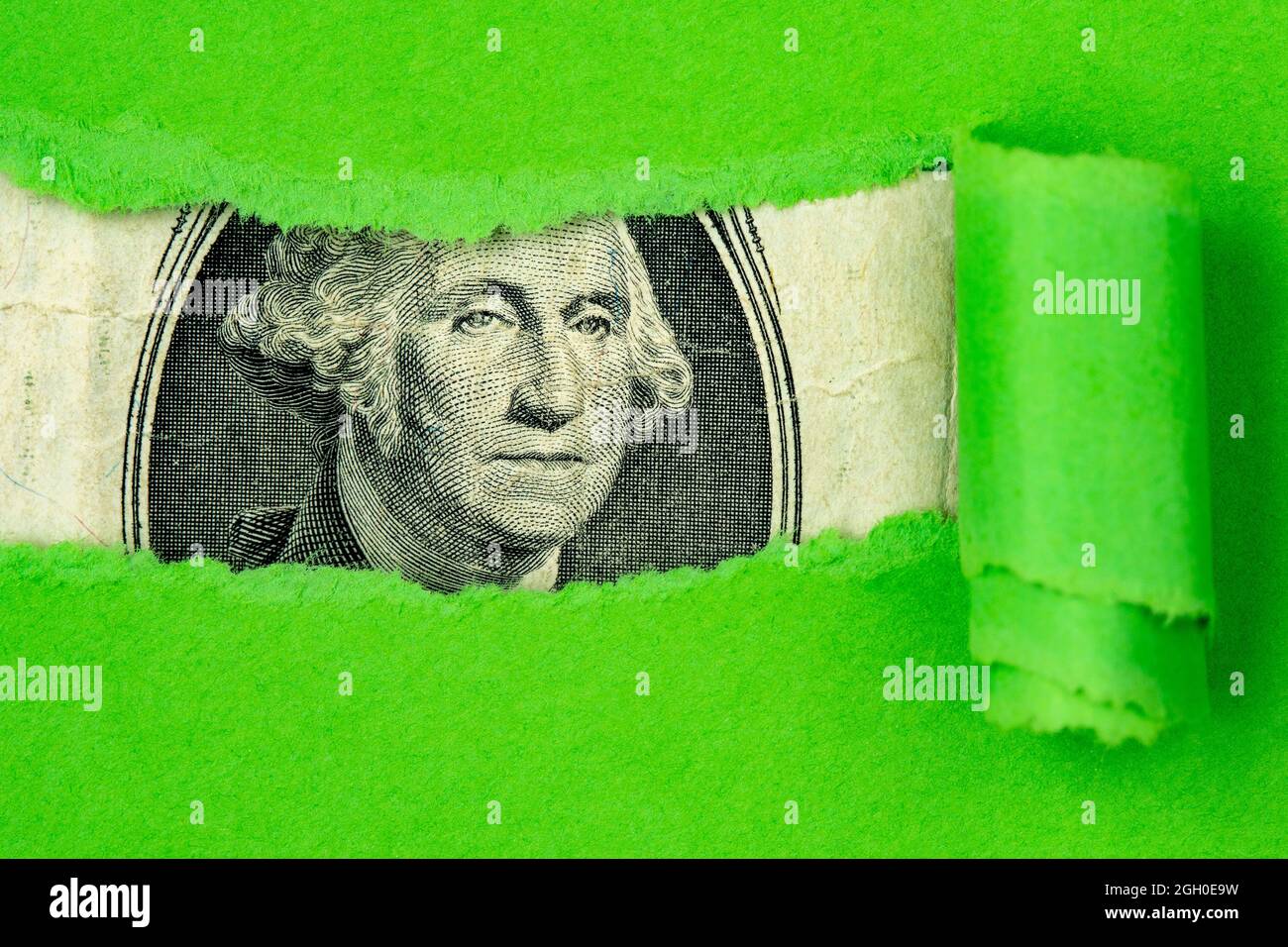US currency macro peeking through torn green paper Stock Photo - Alamy