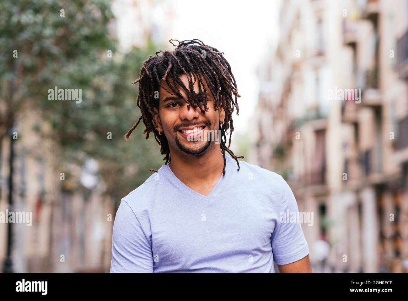 horizontal portrait of an hispanic young man with dreadlocks. He is ...