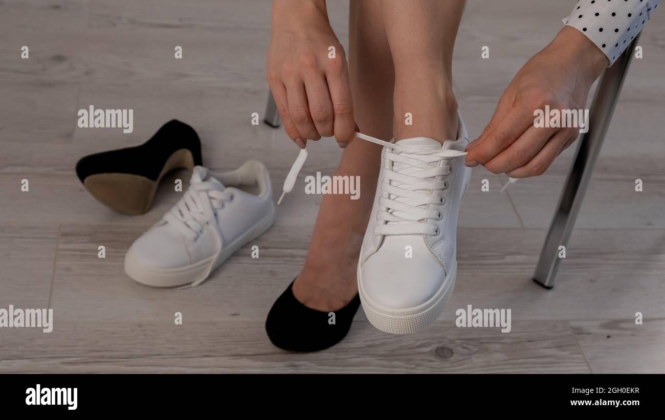 Close-up business woman takes off her shoes puts on white leather ...