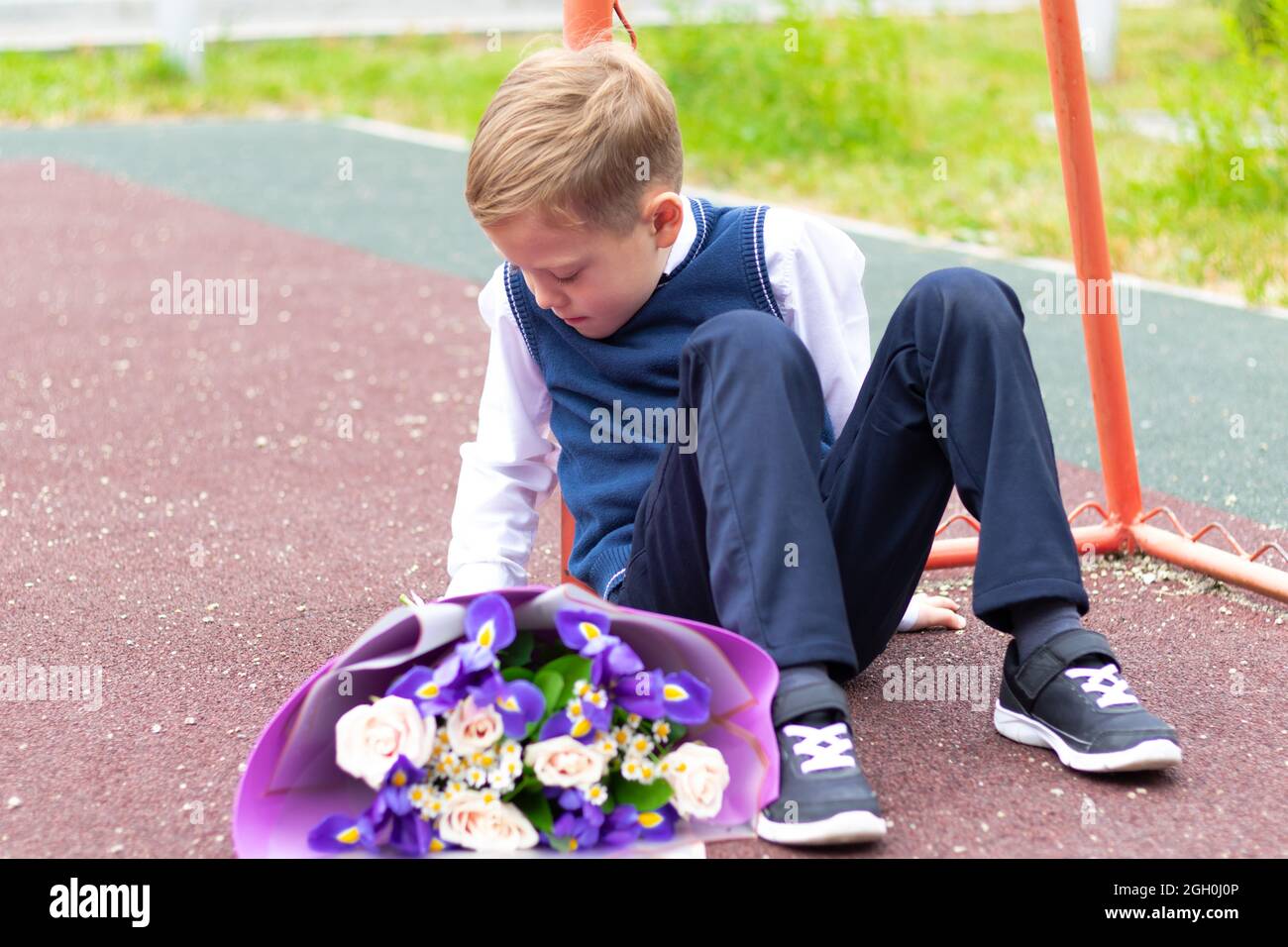 A cute first-grader boy in a school uniform with a beautiful bouquet of ...