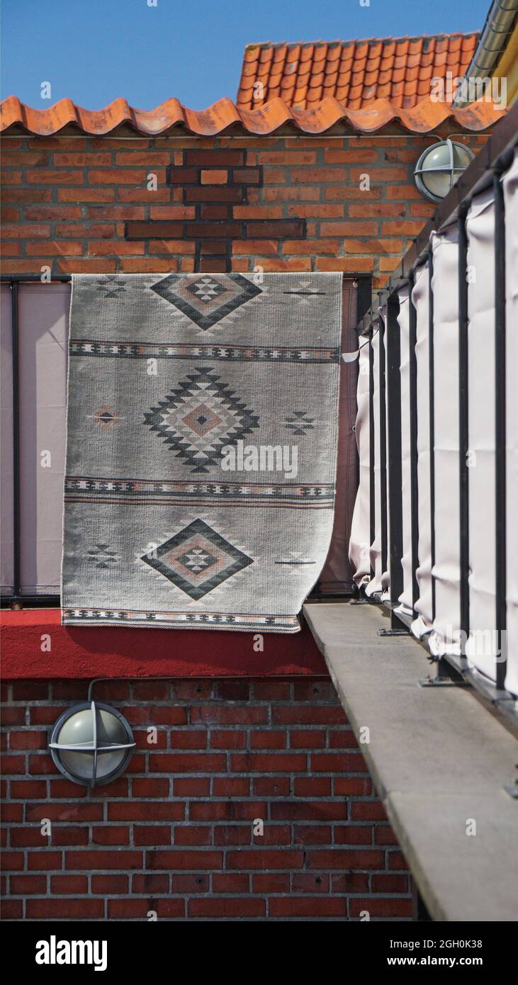 a carpet on a red brick wall forms parallel and vertical lines, Ronne ...