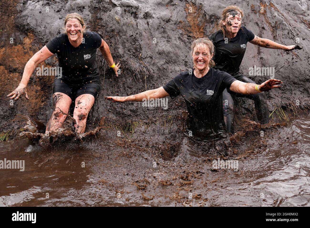 Competitors slip and slide in mud during a Tough Mudder event at ...