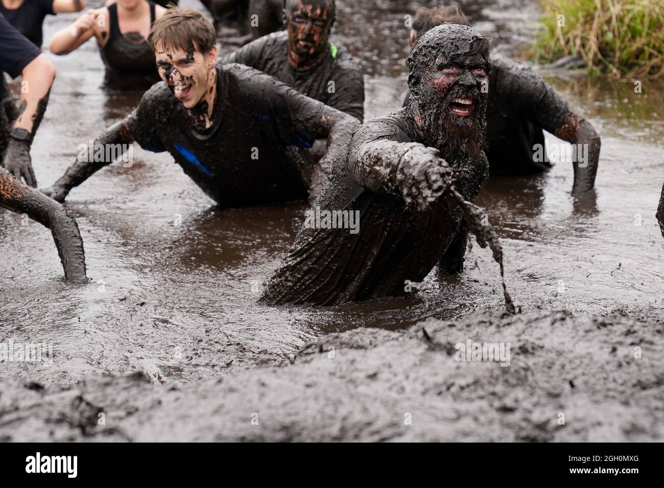 Competitors slip and slide in mud during a Tough Mudder event at ...