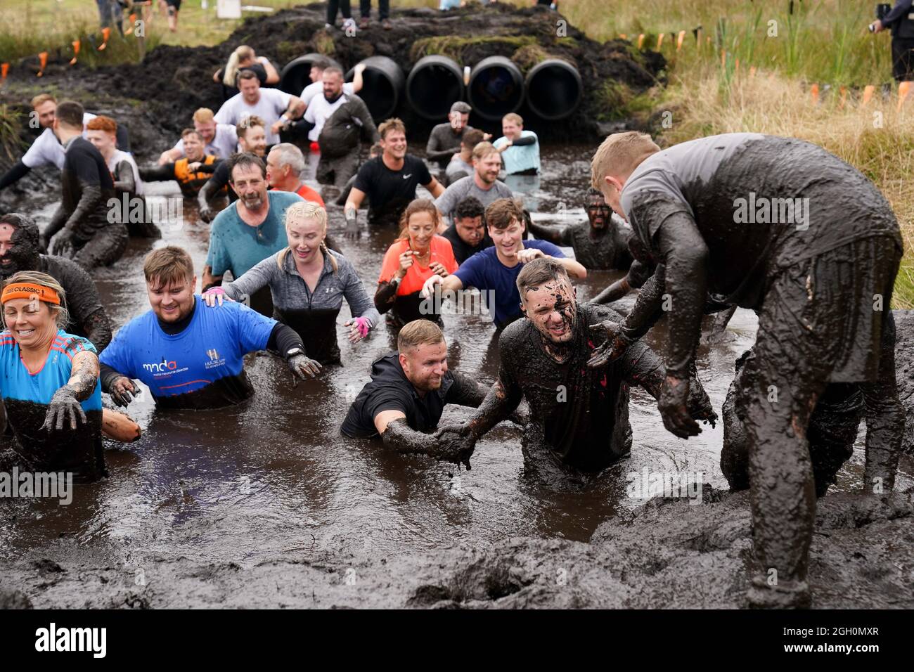 Competitors slip and slide in mud during a Tough Mudder event at ...