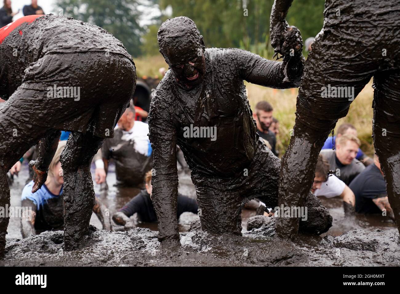 Competitors slip and slide in mud during a Tough Mudder event at ...