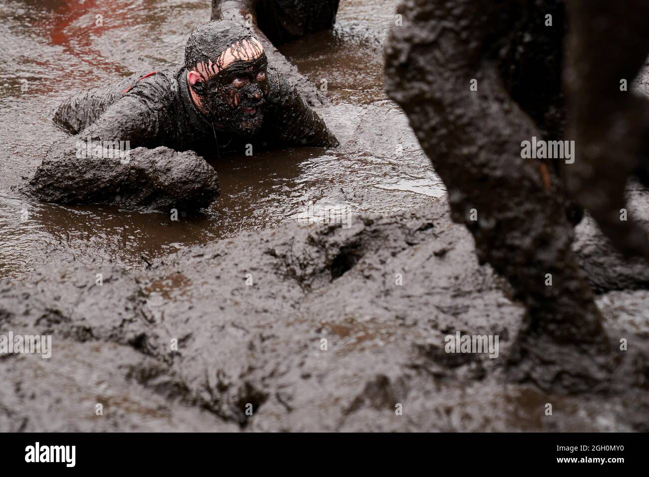 Competitors slip and slide in mud during a Tough Mudder event at ...
