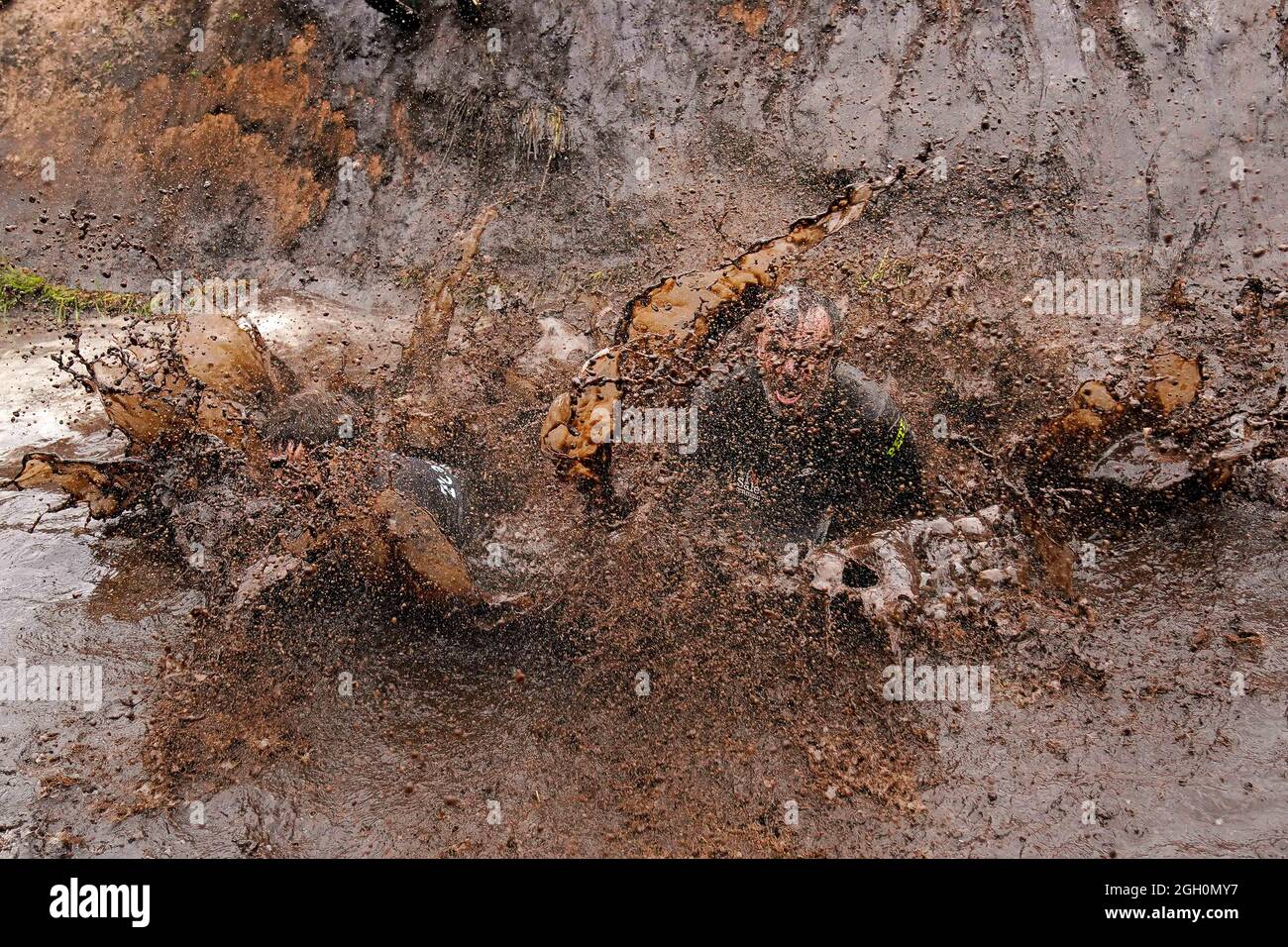 Competitors slip and slide in mud during a Tough Mudder event at ...