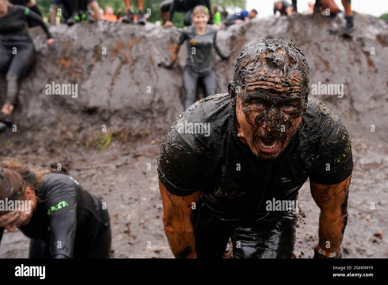 Competitors slip and slide in mud during a Tough Mudder event at ...