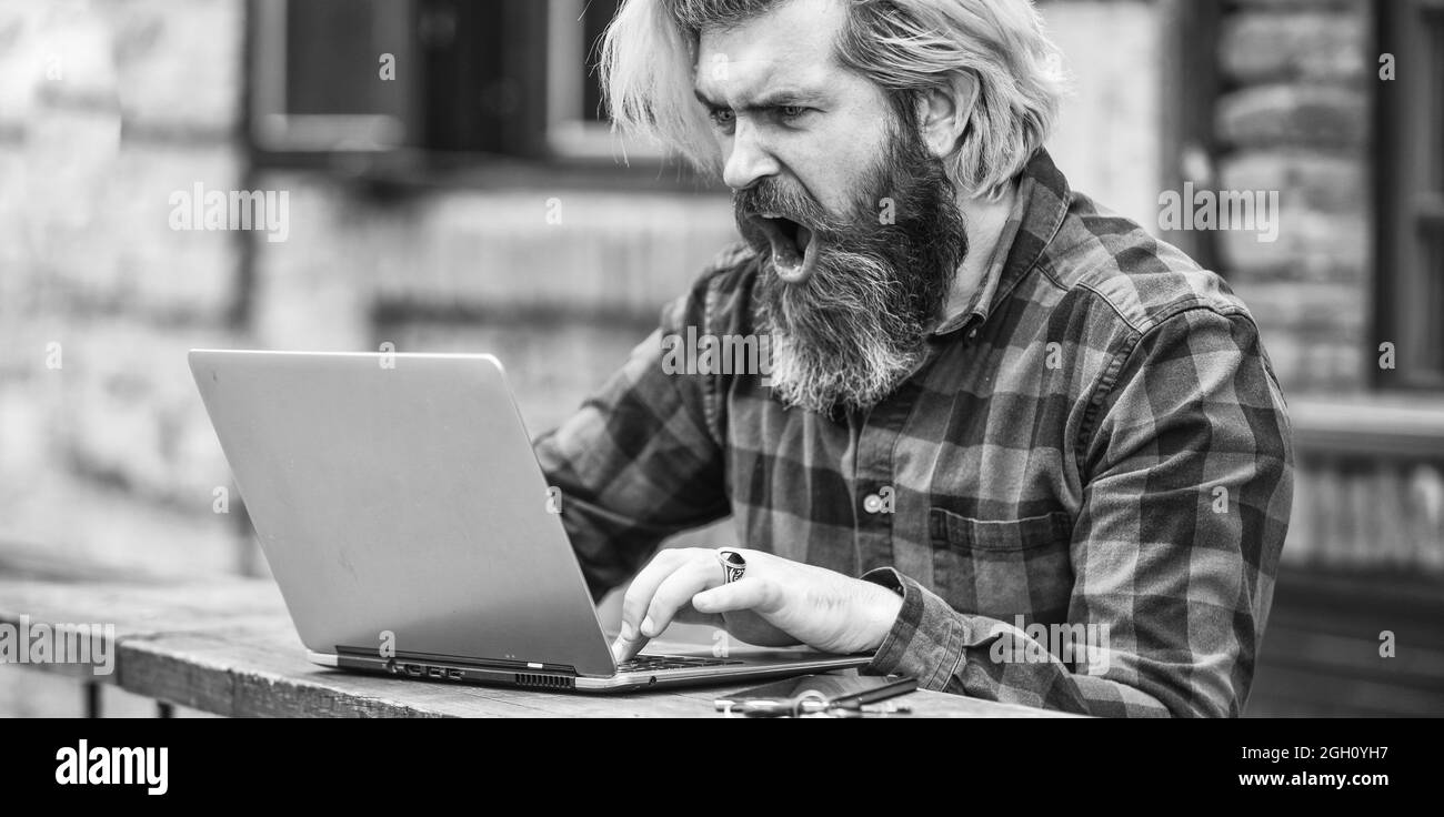 Living in digital age. angry man sitting in cafe with laptop and ...