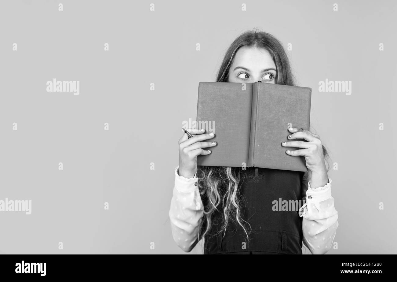 Looking for relevant information. Little girl cover face with book ...