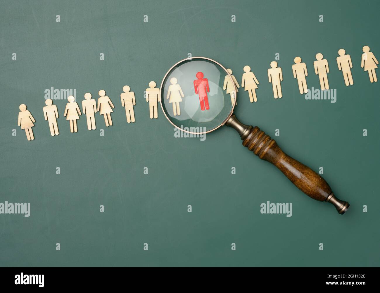 wooden men and a magnifying glass on a green background. Recruitment ...
